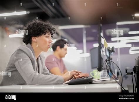 Young Female Software Developer Using Desktop Computer While Writing