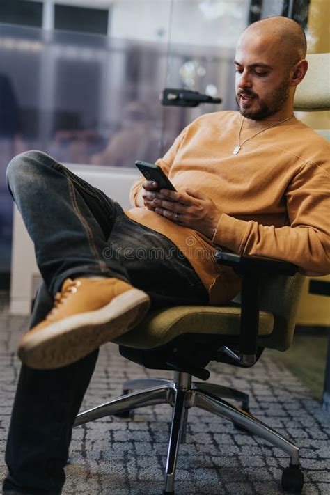 A Young Man In An Office Enjoying A Break From Work Sitting At His Workplace Relaxing And