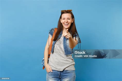 영 웃 배낭 사랑 스러운 여자 학생 오렌지 심장 안경 카메라 파란색 배경에 고립에 검지 손가락을 가리키는의 초상화 고등학교에서 교육입니다 광고에 대 한 공간을 복사 합니다