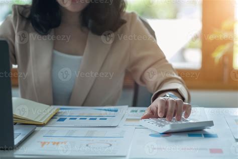 Portrait Of A Female Accountant Using A Calculator And Laptop To Calculate Balance Using Graphs