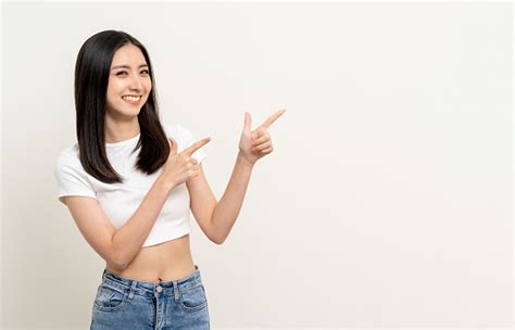 하얀 셔츠를 입은 행복한 아름 다운 아시아 여자가 손가락으로 공간을 복사한다 빈 공간을 가진 웃는 여성 아가씨 아시아의 귀여운