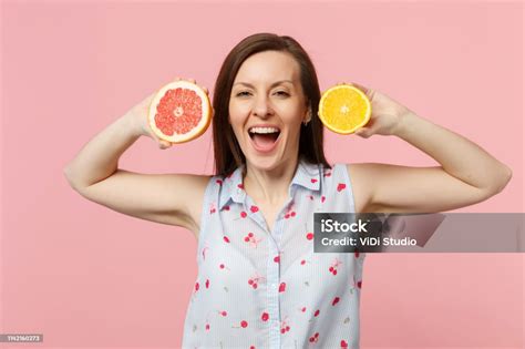 신선한 잘 익은 자 몽 오렌지 과일 분홍색 파스텔 벽 배경에 고립의 Halfs를 들고 여름 옷에 쾌활 한 젊은 여자 사람들은 생생한 라이프 스타일 휴식 휴가 개념입니다 복사