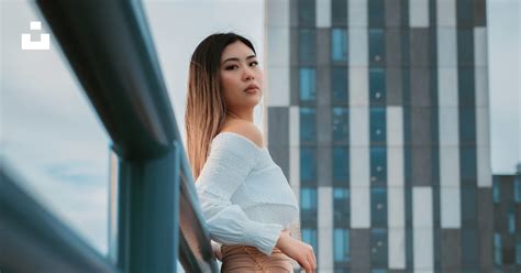 흰 셔츠와 갈색 치마를 입은 여자가 파란색 금속 난간에 기대어 있다 사진 Unsplash의 무료 초상 이미지