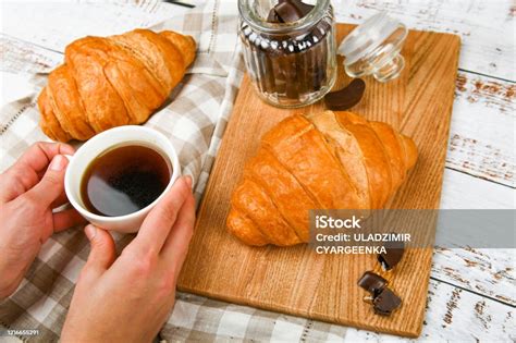 소녀가 커피 잔을 들고 있다 크루아상의 배경에 크루아상과 커피 아침의 시작 커피 컵 커피와 신선한 프렌치 크루아상이 있는 컵을 들고 있는 여성의 손에서 바라보는 탑 뷰