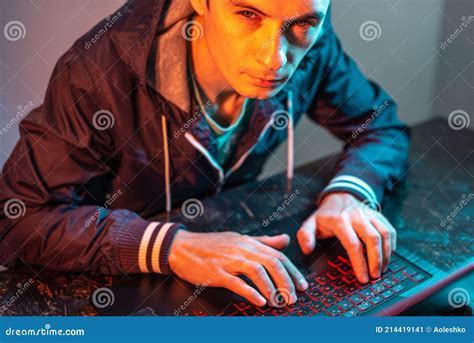 A Male Hacker Is Typing On A Laptop Keyboard In A Dark Room Under A Neon Light Cybercrime Fraud