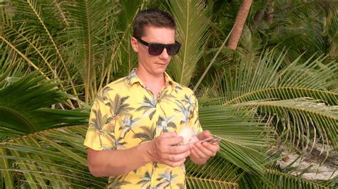 Man Counting Thai Baht On A Beach With Palm Leaves In The Background