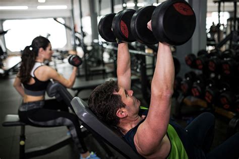 그의 50 대 성숙한 남자 무게와 아령 리프팅에 그의 강도 성능을 향상 시키기 위해 체육관에서 가슴을 자극 하는 훈련 배경에 40 세 여성은 이두근을 훈련 2명에 대한 스톡