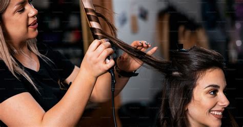 여성 미용사는 살롱에서 갈색 머리를 가진 젊은 여성에게 헤어스타일을 만든다 사진 Unsplash의 세르비아 이미지