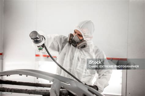 도장 부스에서 페인트 스프레이 건으로 자동차 사고로 피해를 입은 자동차 범퍼에 전체 작업복과 호흡 마스크 스프레이를 그리는