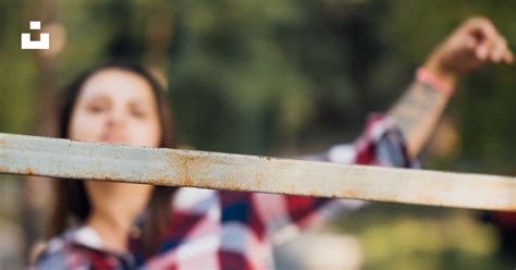 낮 동안 갈색 나무 울타리를 들고 있는 빨간색 흰색과 파란색 격자무늬 드레스 셔츠를 입은 남자 사진 Unsplash의 무료 사람의 이미지