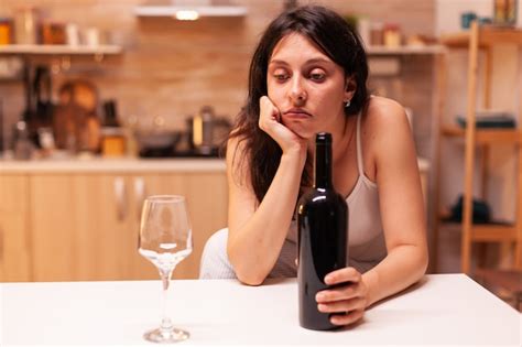 집에서 와인 한 병과 유리잔을 가지고 있는 알코올 중독 여성 우울한 알코올로 음료를 마시는 외로운 사람 중독을 느끼는
