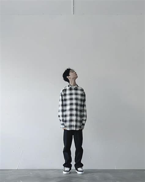 Man Wearing Plaid Shirt And Black Pants Against White Wall Premium Ai