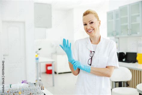 Middle Aged Attractive Lab Assistant In Sterile White Uniform Standing In Laboratory And Putting
