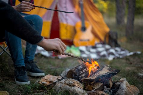 아름 다운 커플 앉아 캠프 파이어 주위에 캠핑 텐트와 배경에 남자 막대기로 화재 제스처 하이킹에 대한 스톡 사진 및 기타 이미지 Istock