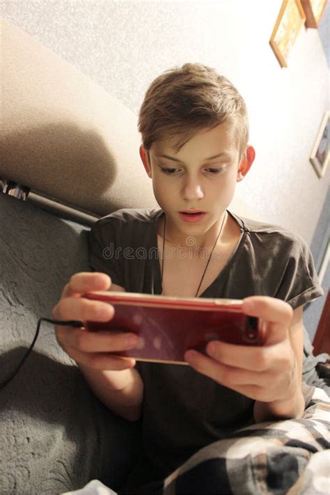 The Guy Sitting On The Couch Plays Games On The Phone In His Spare Time Stock Image Image Of