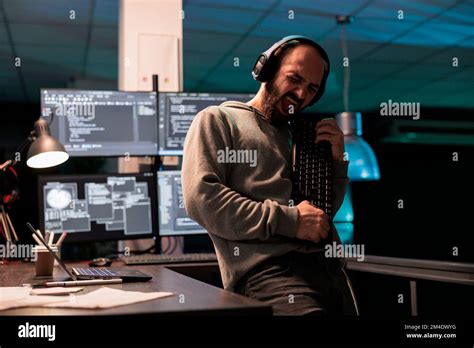 male software engineer playing guitar with keyboard writing code with