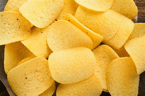 감자 골판지 칩 패스트 푸드 파삭 파삭 한 감자 칩은 오래된 부엌 테이블 나무 배경에 나무 스탠드에 사워 크림 소스와 양파와