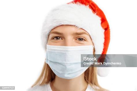 마스크를 쓰고 산타클로스 모자를 쓰고 카메라를 바라보며 하얀 색 배경을 가진 젊은 여성 독감 전염병 코로나바이러스 바이러스 보호 12월에 대한 스톡 사진 및 기타 이미지