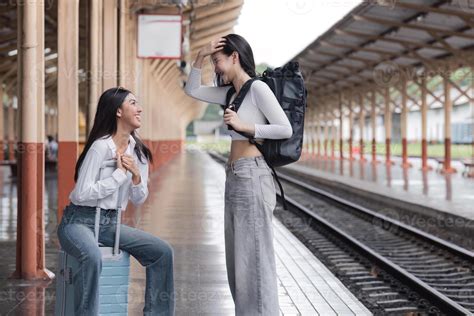 Young Lesbian Couple Waiting For Train At Station Smiling And Enjoying