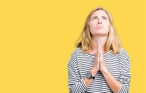 구걸 하 고 손으로 얼굴 매우 감정적이 고 걱정에 희망 식 함께 기도 격리 된 배경 위에 줄무늬 스웨터를 입고 아름 다운 젊은 여자 용 서에 대 한 요구 종교 개념입니다