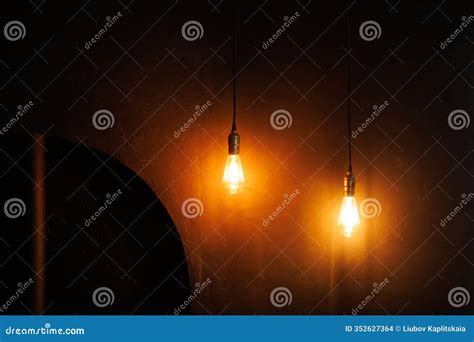 Two Dark Light Bulbs On A Long Cord Are Twined From The Ceiling Stock