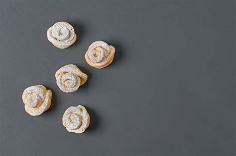 가루 설탕의 장미 스팽글 형태로 흩어져 만든 구운 빵은 어두운 콘크리트 책상에 놓여있다 제과 작업장 텍스트의 공백입니다 맨 위