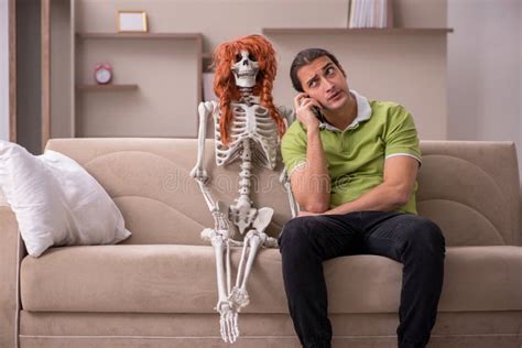 Young Man Sitting On The Sofa With Female Skeleton Stock Image Image