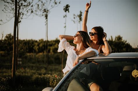 열린 창문을 통해 차에서 놀고있는 도로 여행에서 선글라스를 쓴 두 명의 여성 친구 20 24세에 대한 스톡 사진 및 기타 이미지 20 24세 25 29세 2명
