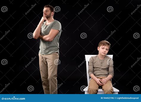 Будьте отцом положения с рукой на подбородке и осадите мальчика сидя на табуретке Стоковое Фото