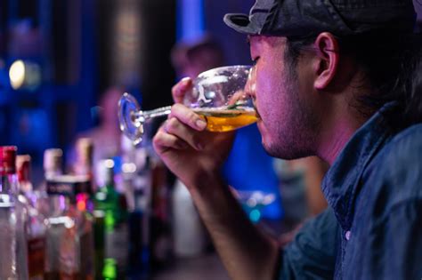 아시아 우울증 남자는 마음이 상하고 술집에서 맥주를 마시는 느낌 카운터 바에 앉아 외로움을 느끼는 술 한 병을 들고 나이트 클럽에서 혼자 술에 취해 숙취를 느끼는 매력적인