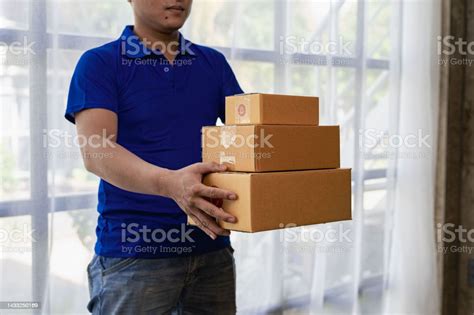 파란색 모자와 파란색 티셔츠를 입은 행복한 청년이 흰색 배경에 고립 된 노란색 상자를 들고 서있는 사진 배달 개념 건강 진단에 대한 스톡 사진 및 기타 이미지 Istock