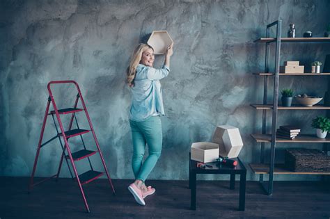 전체 길이 바디 사이즈 프로필 측면 보기 좋은 매력적인 쾌활 한 쾌활 한 물결 모양의 머리 소녀 매달려 선반 회색 벽에 플랫