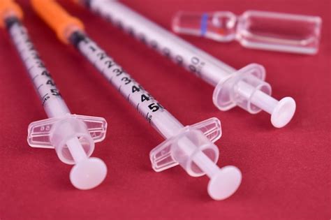 Premium Ai Image Insulin Syringes On A Red Backgroundclose Up