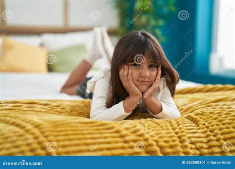 Adorable Hispanic Girl Smiling Confident Lying On Bed At Bedroom Stock