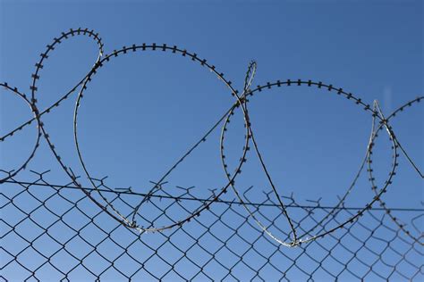 건축 세부 경계 경계 마커 경비가있는 고립된 공공 안전 금속 금속 와이어 날카로운 낮 둘레 루프 와이어 맑은 날 맑은 하늘 방어 방어선 방어적인