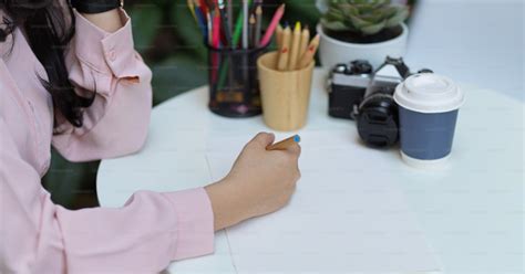 카페의 커피 테이블에 있는 모형 종이에 손으로 그림을 그리는 여학생의 자른 샷 사진 Unsplash의 태국 이미지