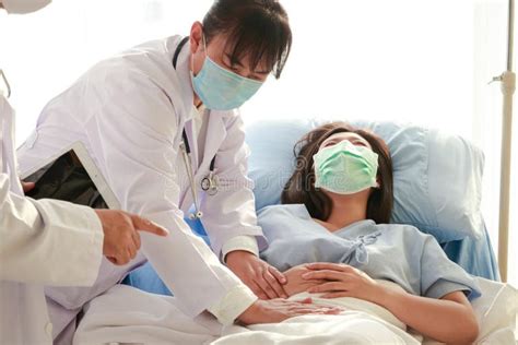 Asian Female Doctor Examines The Abdominal Pain Of A Patient Lying On A