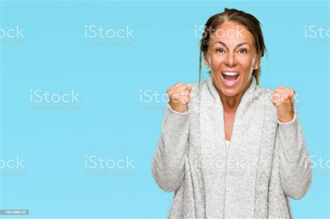 축 하 하는 고립 된 배경 위에 겨울 스웨터를 입고 아름 다운 중 년 성인 여자 놀라게 무기 제기와 성공을 위한 깜짝 놀라게 고 눈을 엽니다 우승자 개념입니다 가을에 대한