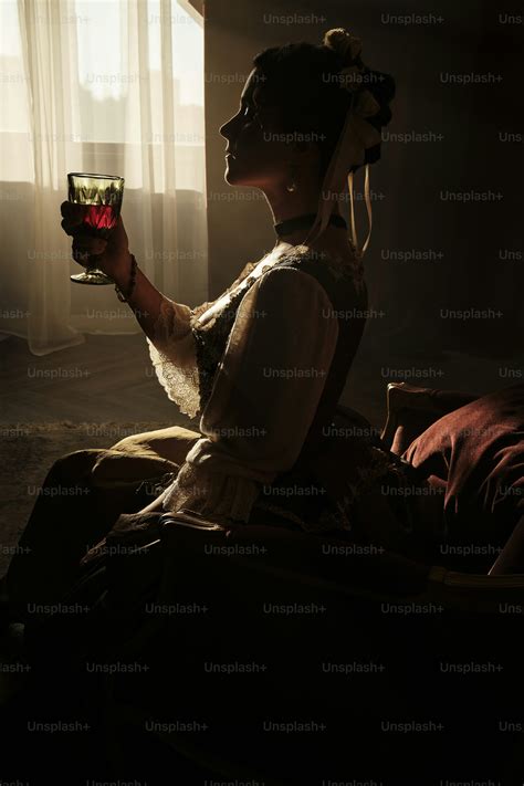 와인 한 잔을 들고 소파에 앉아 있는 여자 사진 Unsplash의 왕족 이미지
