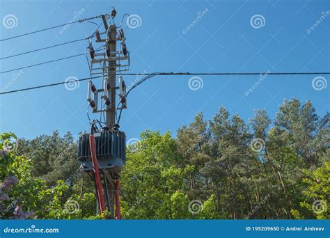 Grey Distribution Transformer Connected To Incoming Power Cables From Above And Output Cables