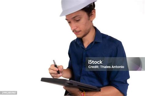 하얀 헬멧을 쓴 젊은 건축가 앉아 태블릿으로 작업하고 있습니다 흰색 배경에 고립되어 있습니다 20 24세에 대한 스톡 사진 및 기타 이미지 Istock