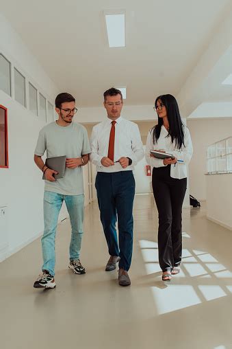 감독은 대기업의 현대적이고 넓은 복도에서 비서 및 젊은 프로그래머와 대화를 나누며 다양한 비즈니스 주제와 프로젝트에 대해 논의합니다 감독에 대한 스톡 사진 및 기타 이미지