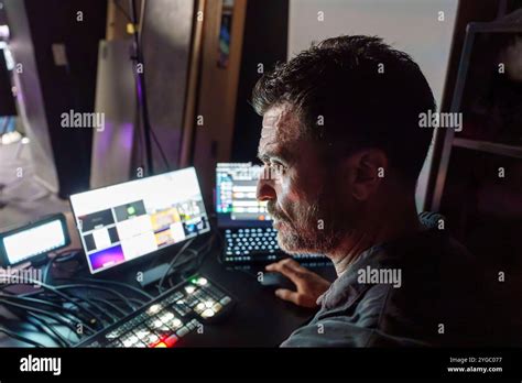 Cybersecurity Professional Analyzing Data On Multiple Screens In A Low Light Workspace For