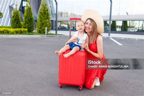 빨간 여행 가방을 든 공항에서 아기 아들을 둔 행복한 엄마가 여름에 여행이나 휴가를 떠납니다 가족에 대한 스톡 사진 및 기타