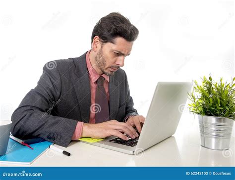 Businessman In Suit And Tie Sitting At Office Desk Working On Computer Laptop Looking