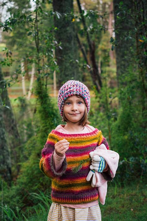 Young Girl With A Rainbow Sweater Standing In A Forest By Stocksy