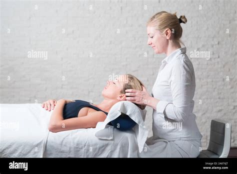 Professional Female Masseur Giving Relaxing Massage Treatment To Young