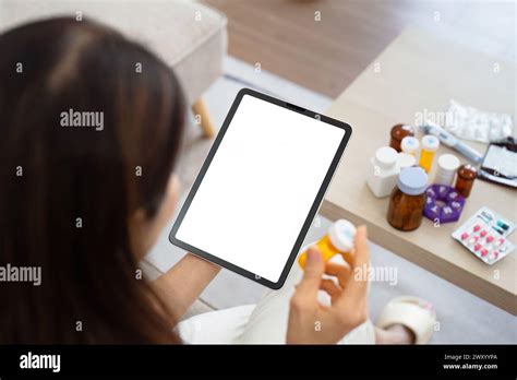 Senior Woman Examining Medication Next To Tablet With Blank Screen Home Healthcare And
