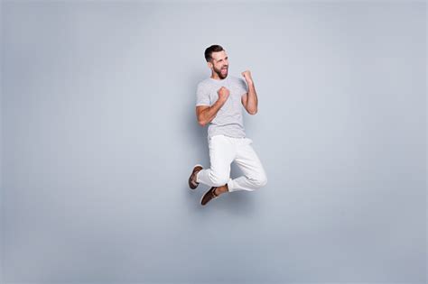 그의 전체 길이 바디 크기 보기 그의 좋은 매력적인 적합 근육 질의 쾌활한 쾌활한 기쁜 수염 남자 점프 기뻐하는 재미 를 통해 고립 된 밝은 회색 파스텔 색상 배경 남자에