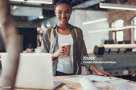 현대 사무실에서 포즈를 취한 뜨거운 음료와 매력적인 아프리카 아메리칸 레이디 노트북에 대한 스톡 사진 및 기타 이미지 노트북
